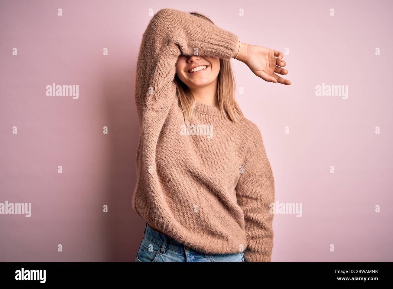 Young beautiful blonde woman wearing winter wool sweater over pink ...