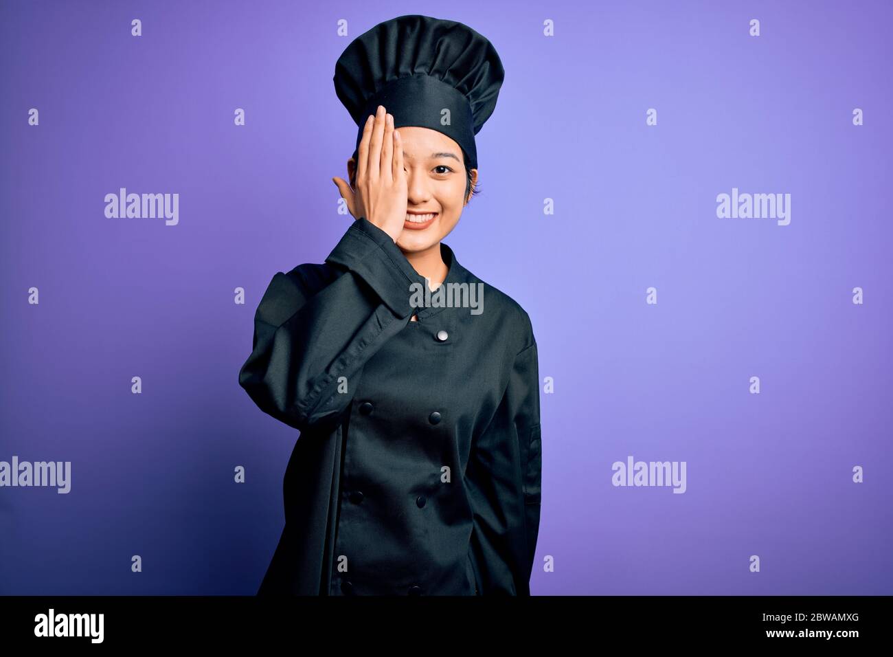 Young beautiful chinese chef woman wearing cooker uniform and hat over ...