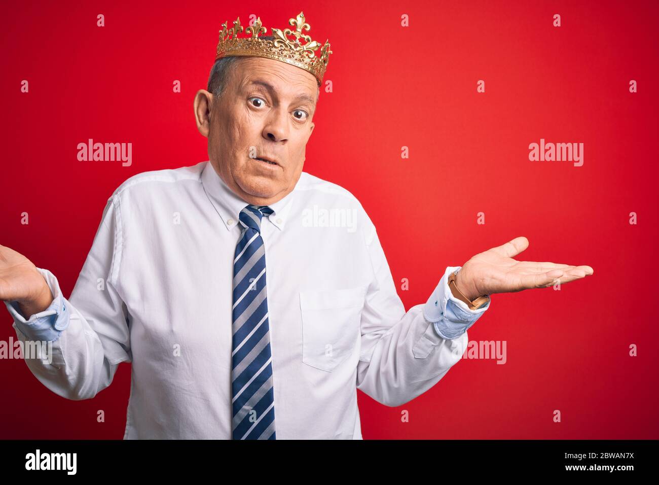 Senior handsome businessman wearing king crown standing over isolated ...