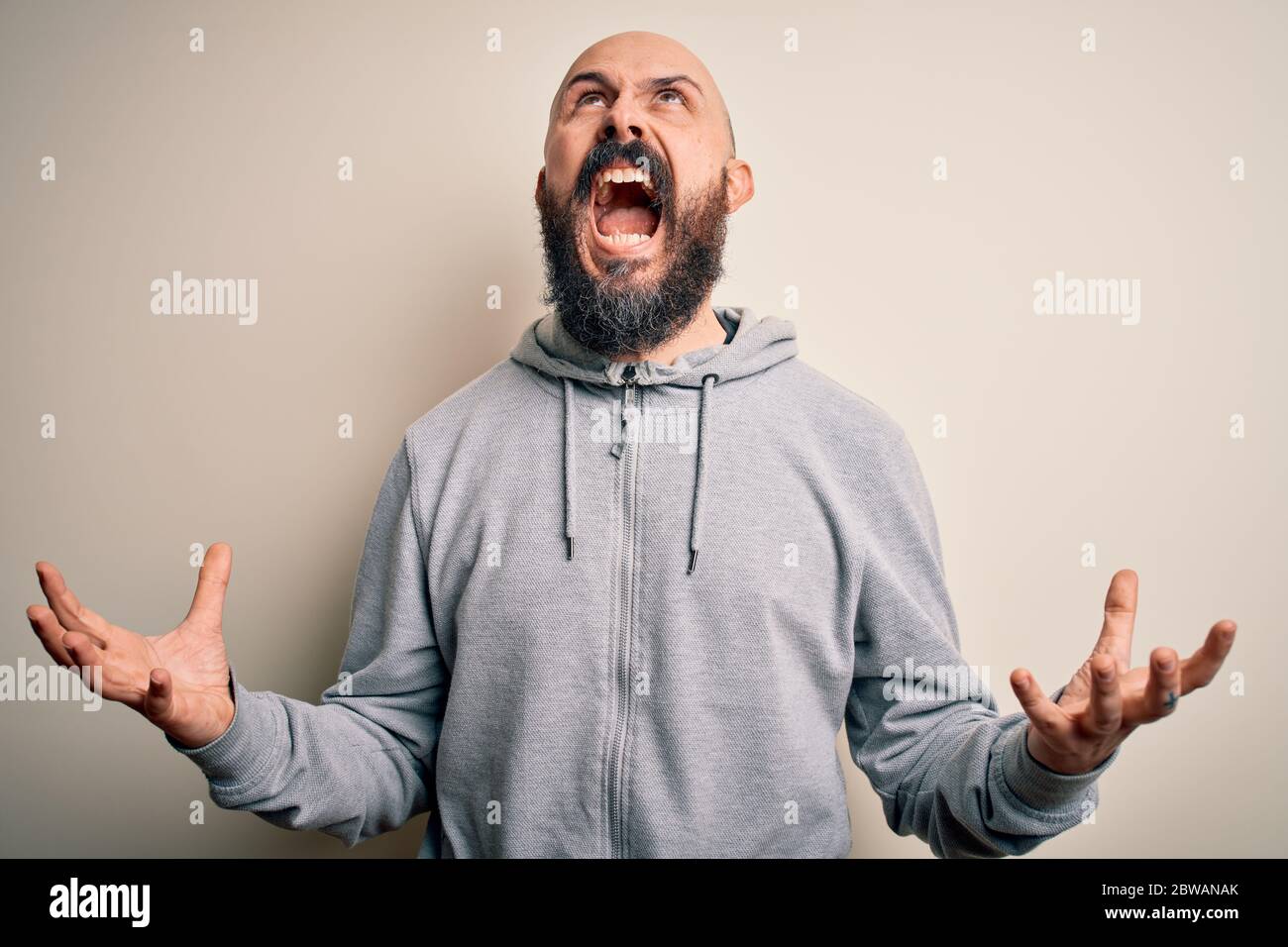 Handsome sporty bald man with beard wearing sweatshirt standing over ...