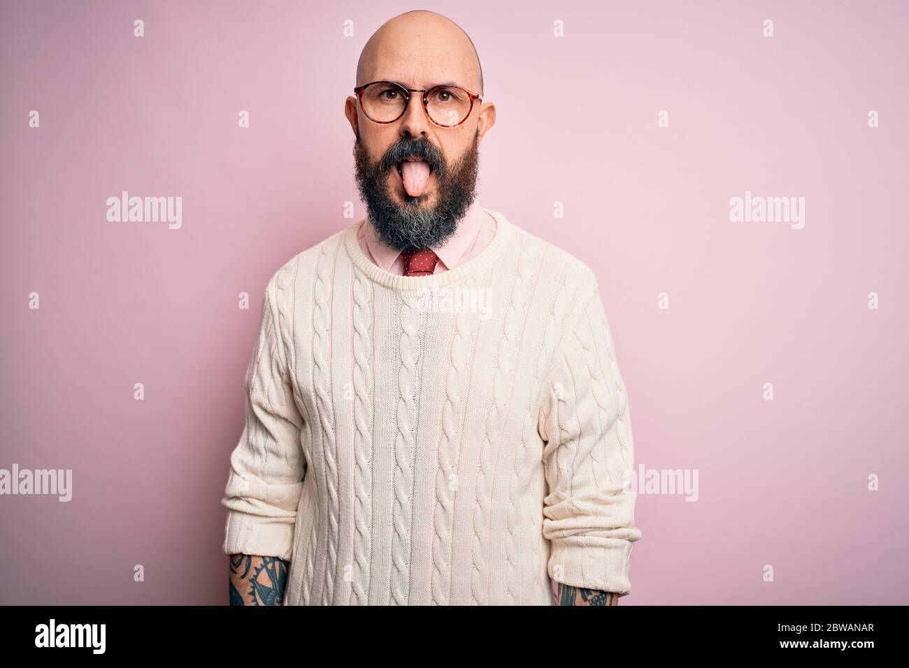 Handsome bald man with beard and tattoo wearing glasses and sweater ...