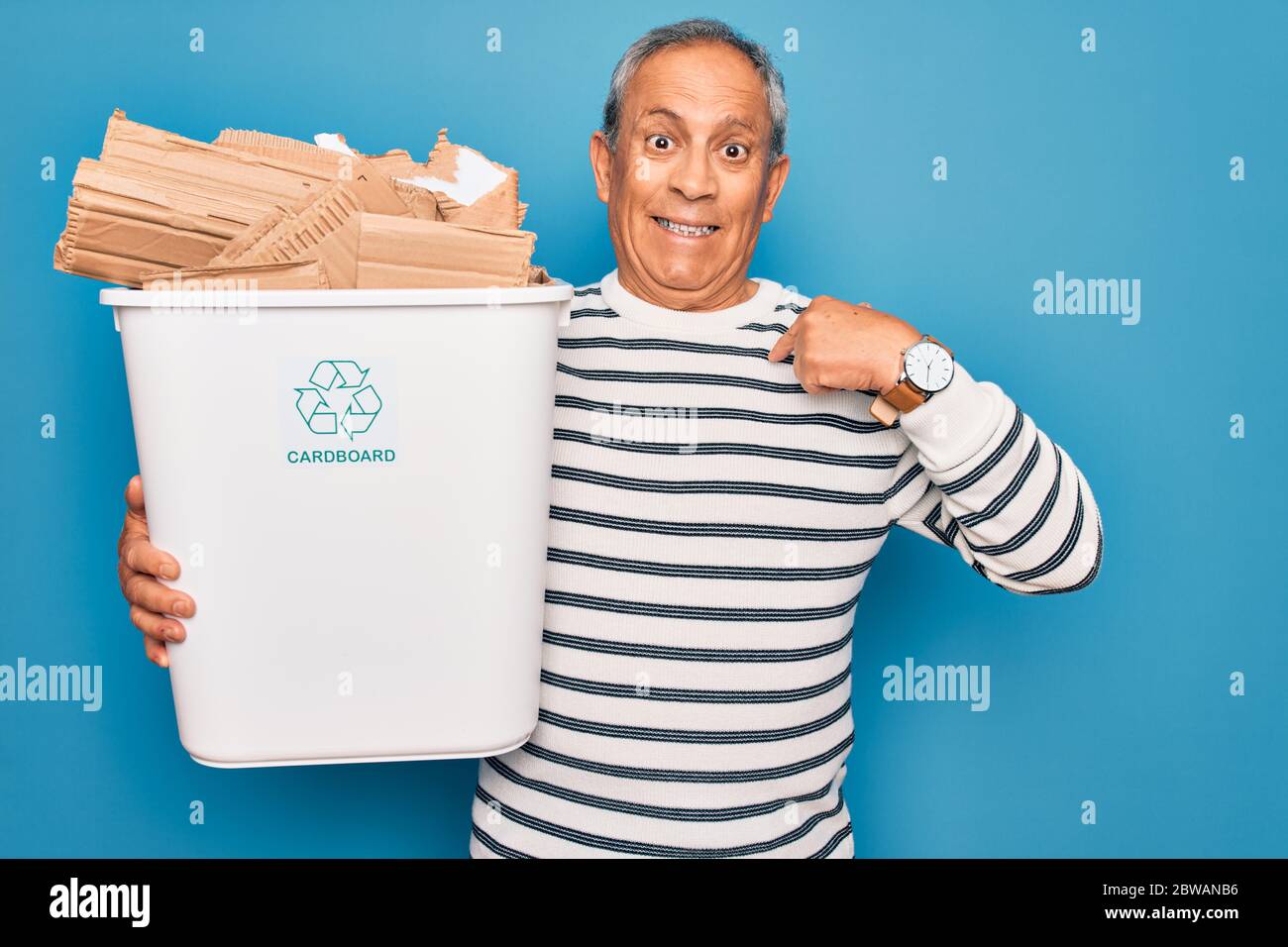 Senior man recycling holding trash can with cardboard to recycle over ...
