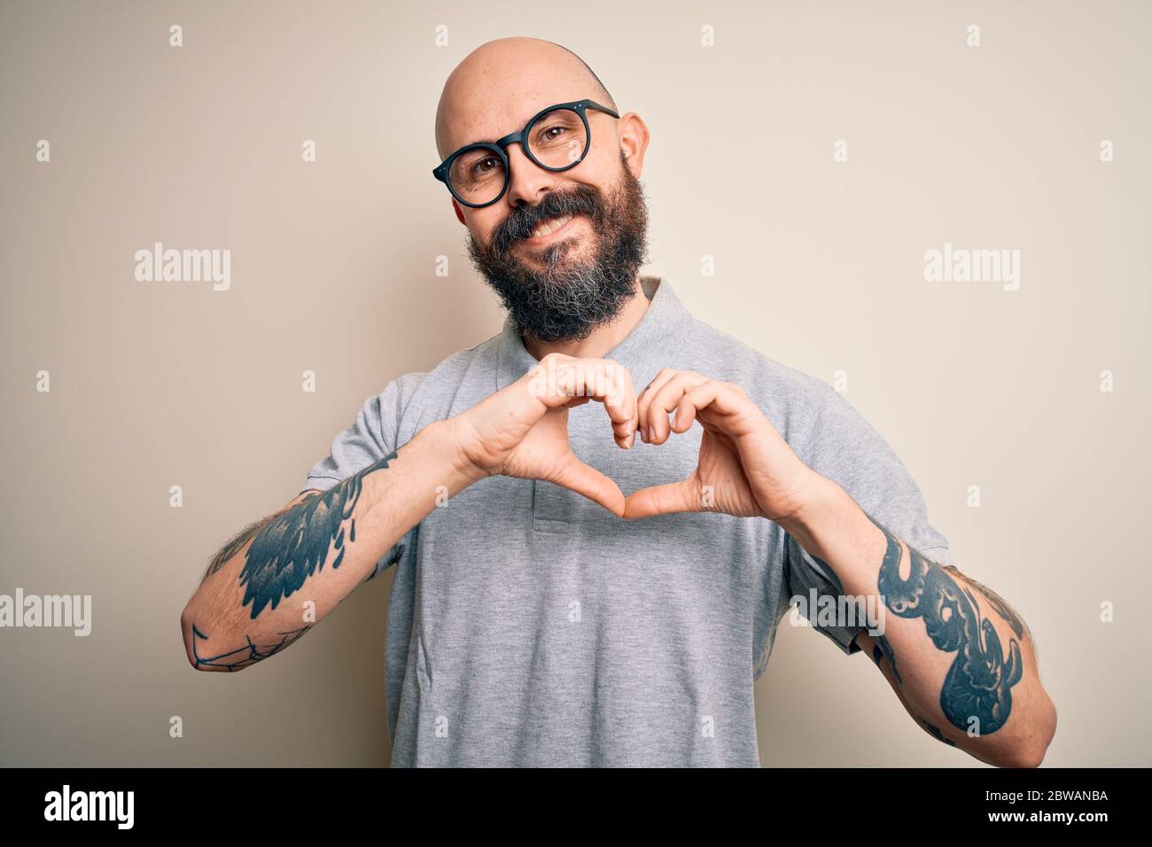 Handsome bald man with beard and tattoo wearing casual polo and glasses ...