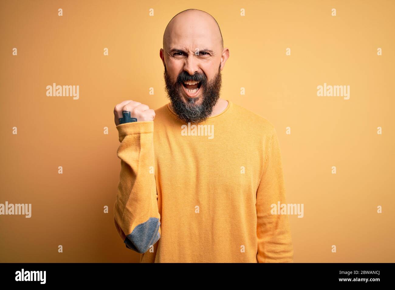 Handsome bald man with beard wearing casual sweater standing over ...