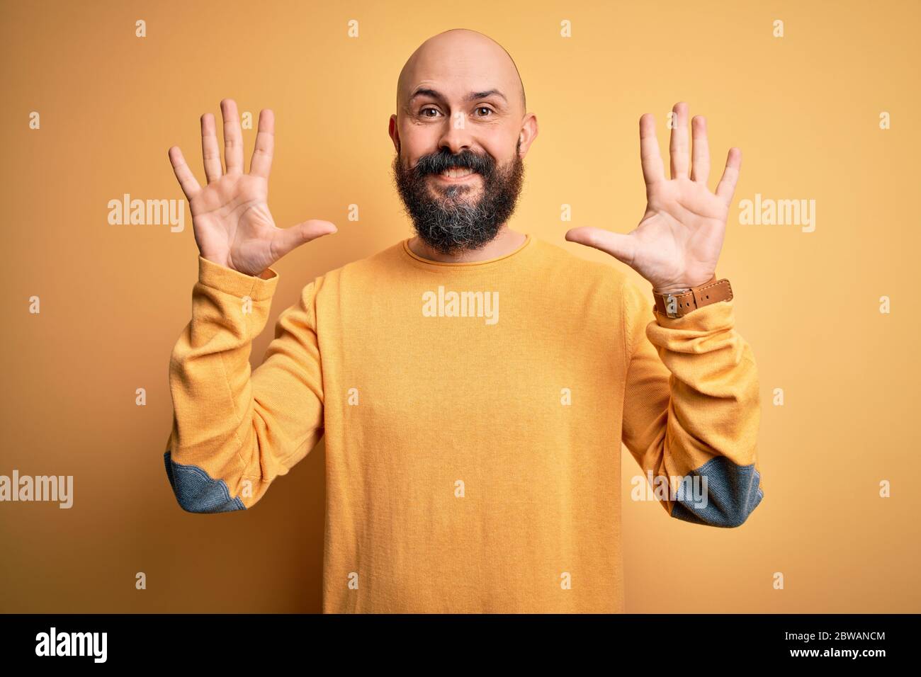 Handsome bald man with beard wearing casual sweater standing over ...