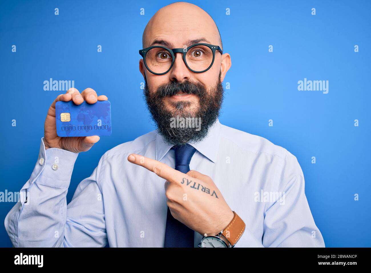 Handsome bald business man with beard holding credit card over isolated ...