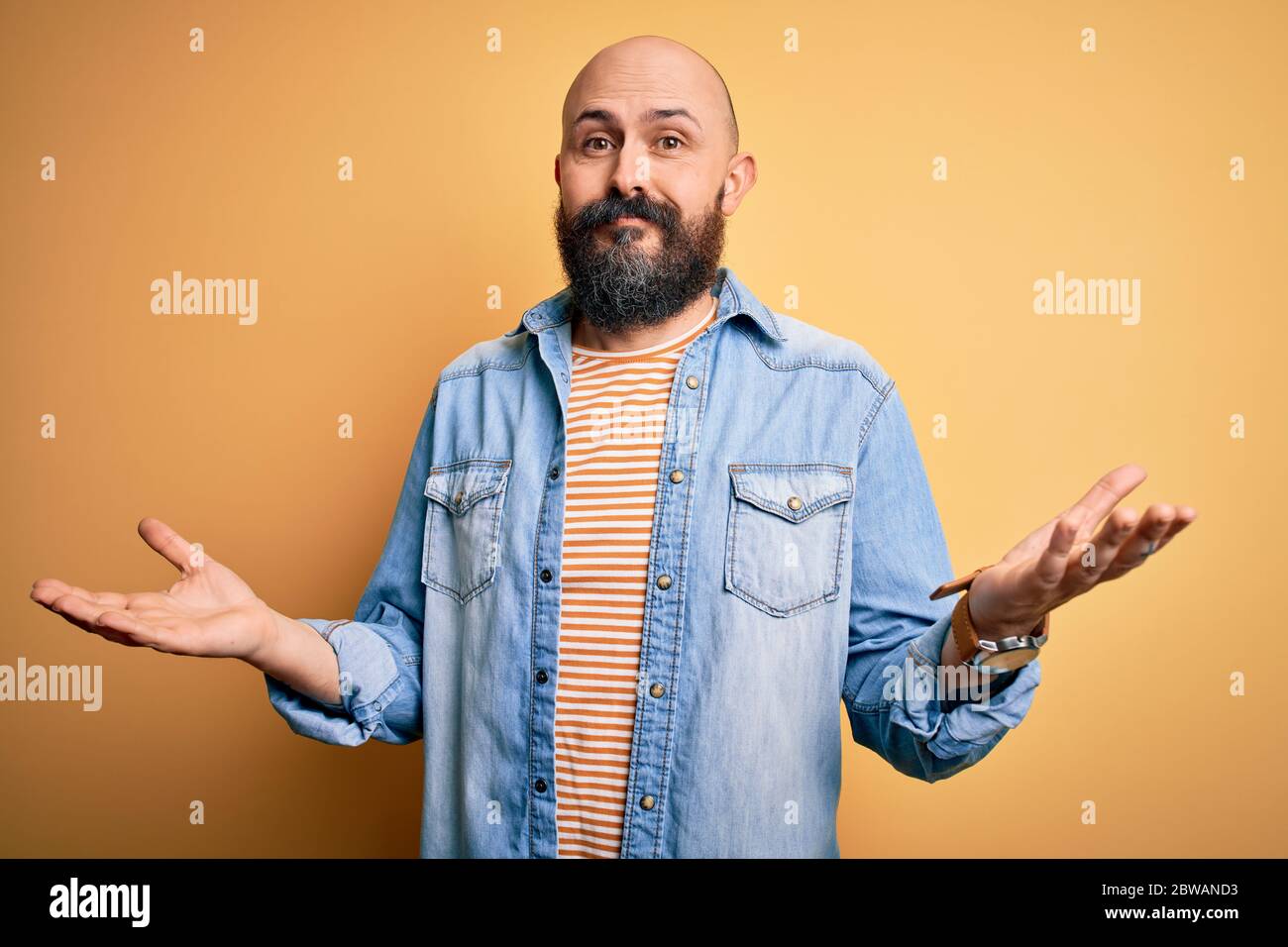 Handsome bald man with beard wearing casual denim jacket and striped t ...