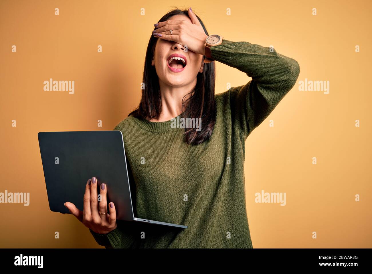 Young brunette woman with blue eyes working using computer laptop over ...