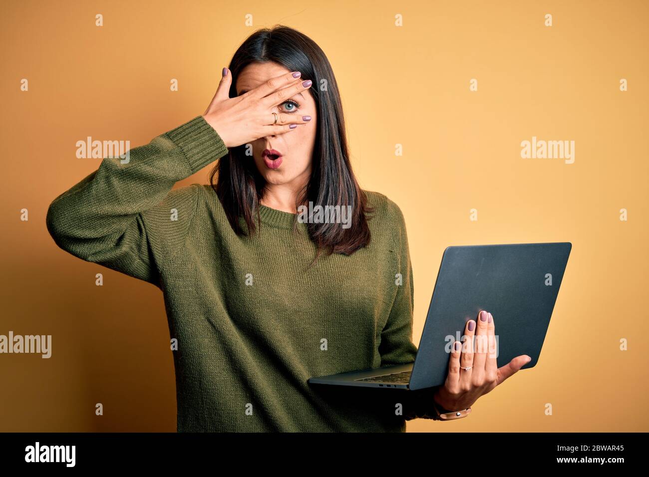 Young brunette woman with blue eyes working using computer laptop over ...