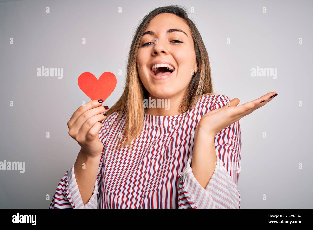 Young beautiful blonde romantic woman holding red paper heart over ...