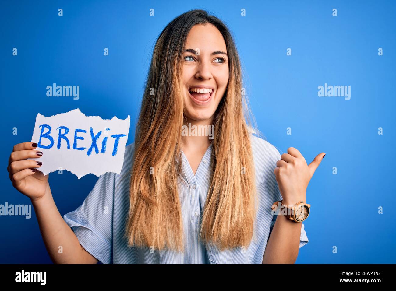 Young beautiful blonde woman with blue eyes holding banner with brexit ...