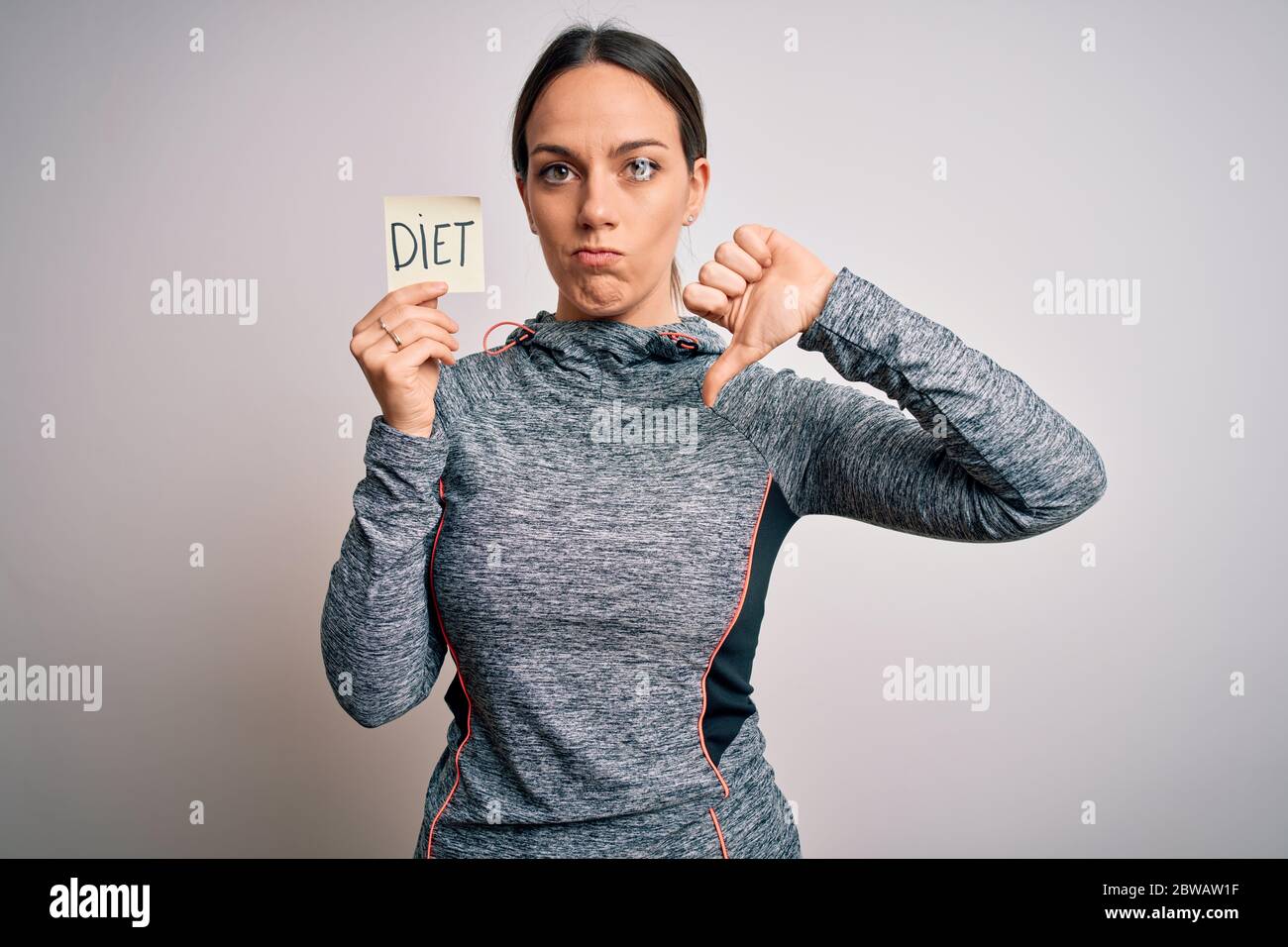Young fitness woman wearing sport workout clothes holding paper with ...