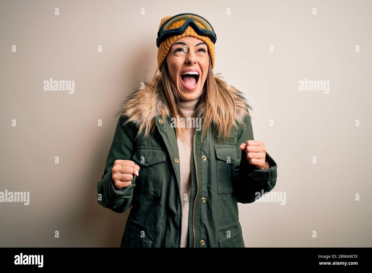 Young brunette skier woman wearing snow clothes and ski goggles over ...