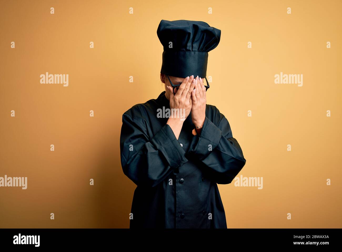 Young beautiful brunette chef woman wearing cooker uniform and hat over ...