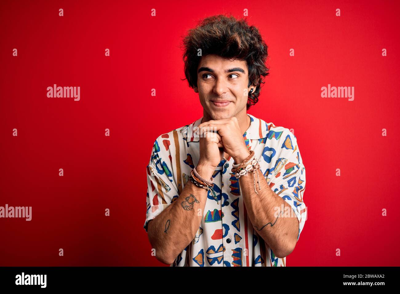 Young handsome man on vacation wearing summer shirt over isolated red ...