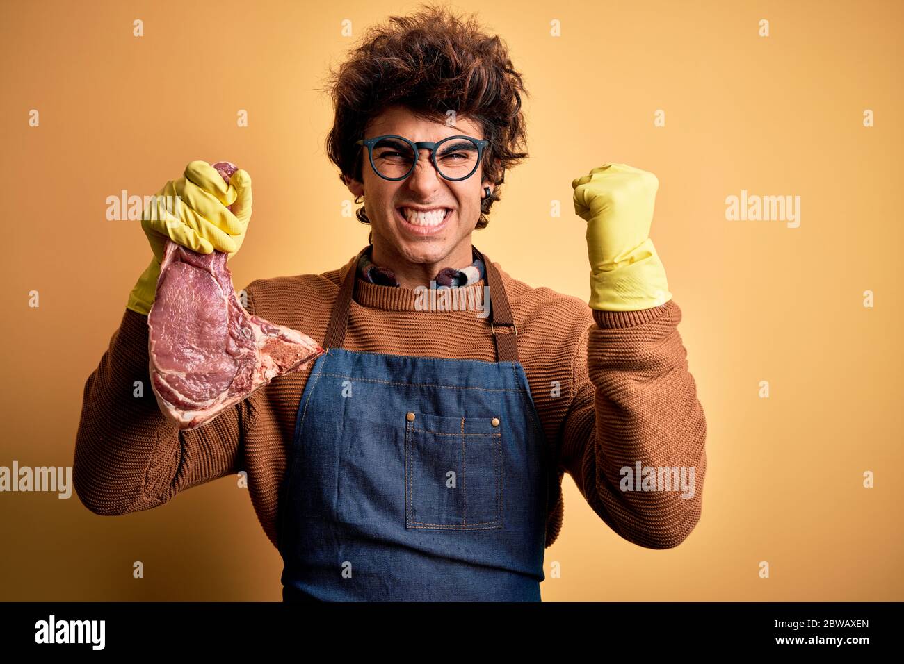 Young handsome butcher man holding meet steak standing over isolated ...