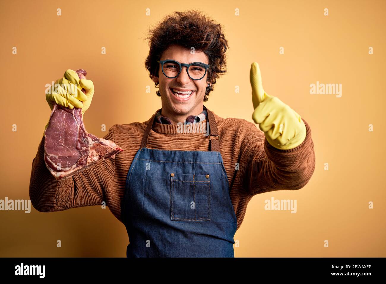Young handsome butcher man holding meet steak standing over isolated ...