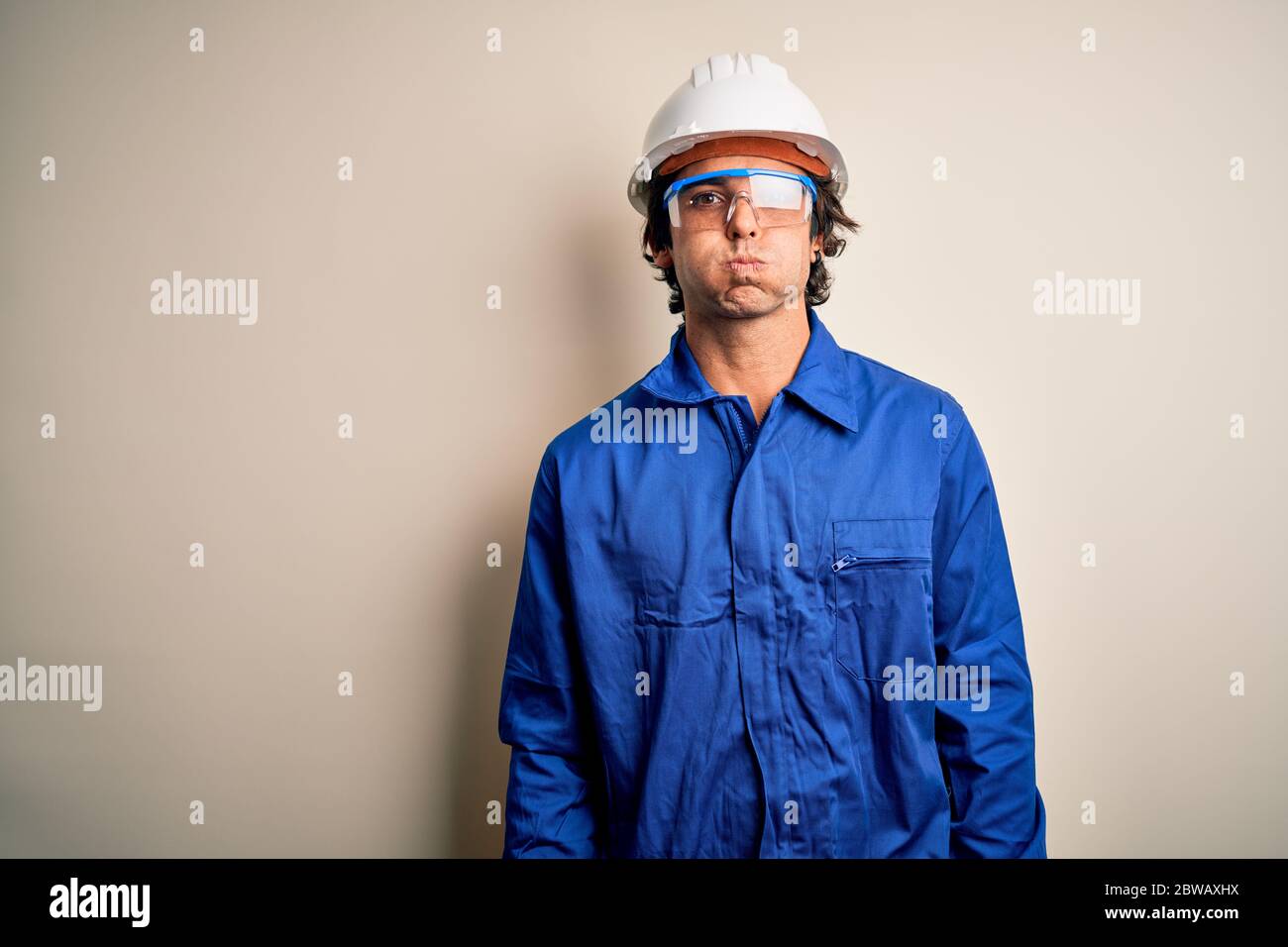 Young constructor man wearing uniform and security helmet over isolated ...