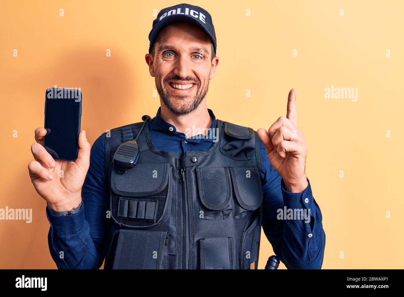 Handsome policeman wearing uniform and bulletprof holding smartphone ...