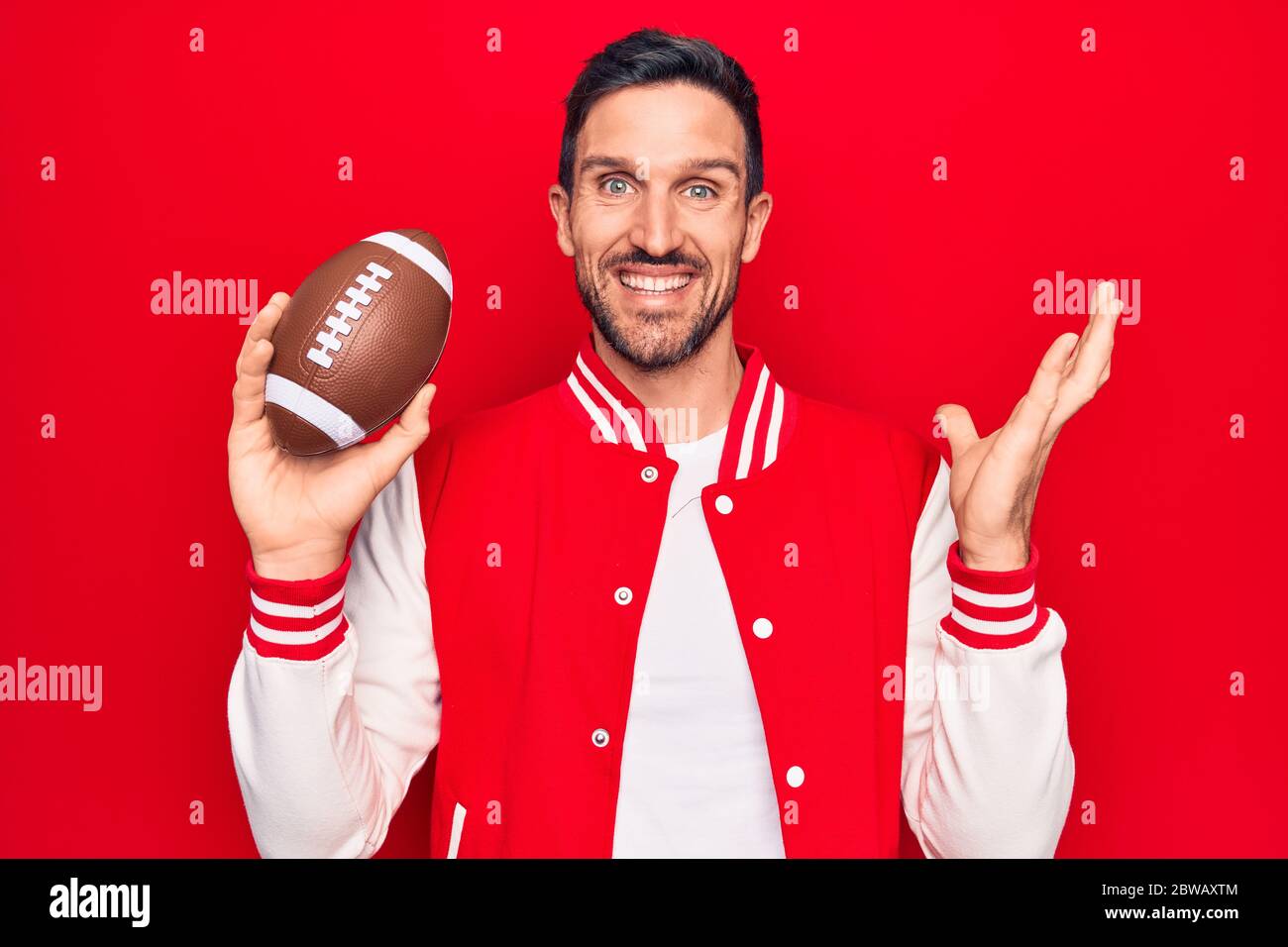 Young handsome player man playing rugby using football ball over ...