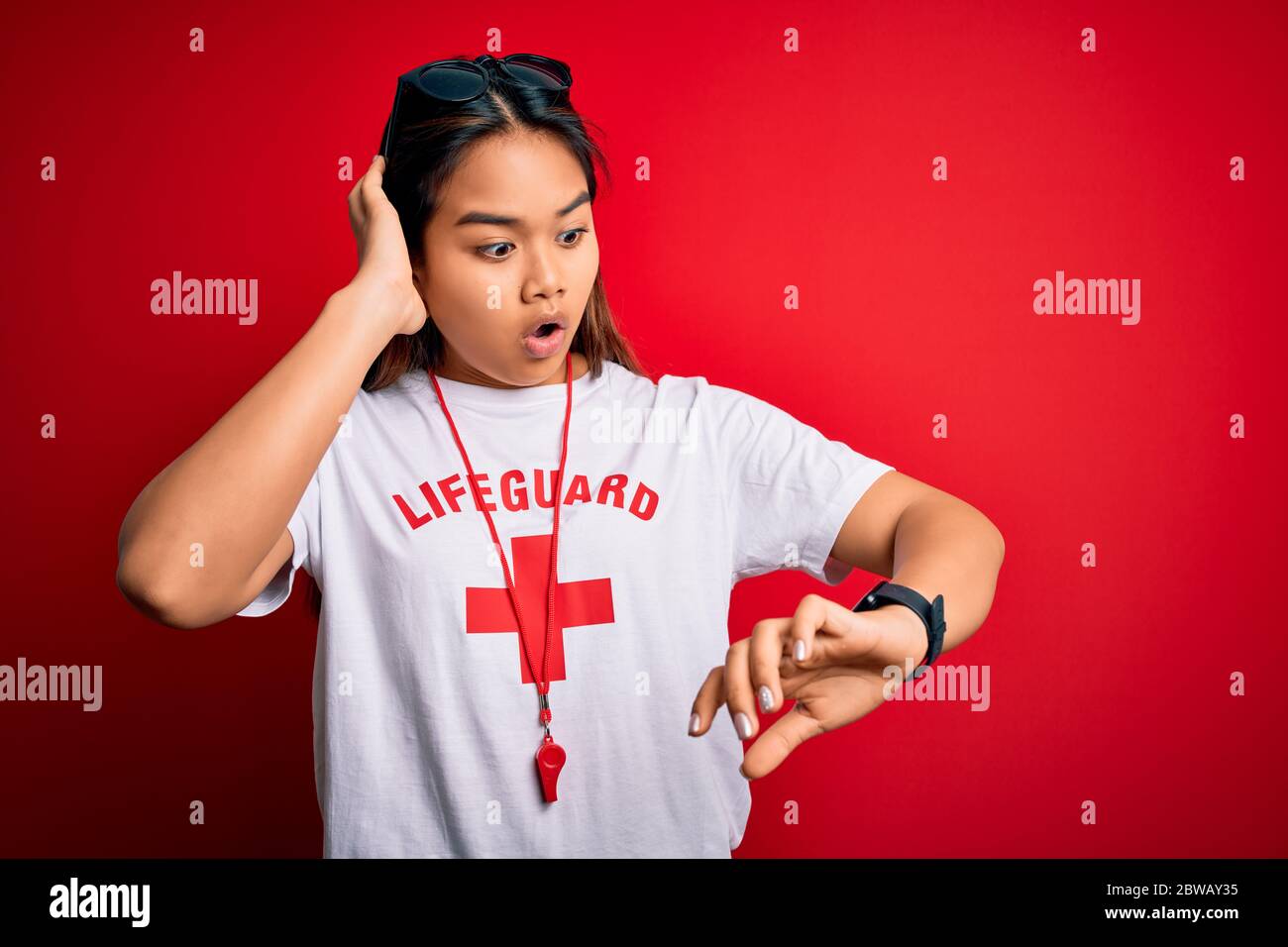 Young asian lifeguard girl wearing t-shirt with red cross using whistle ...