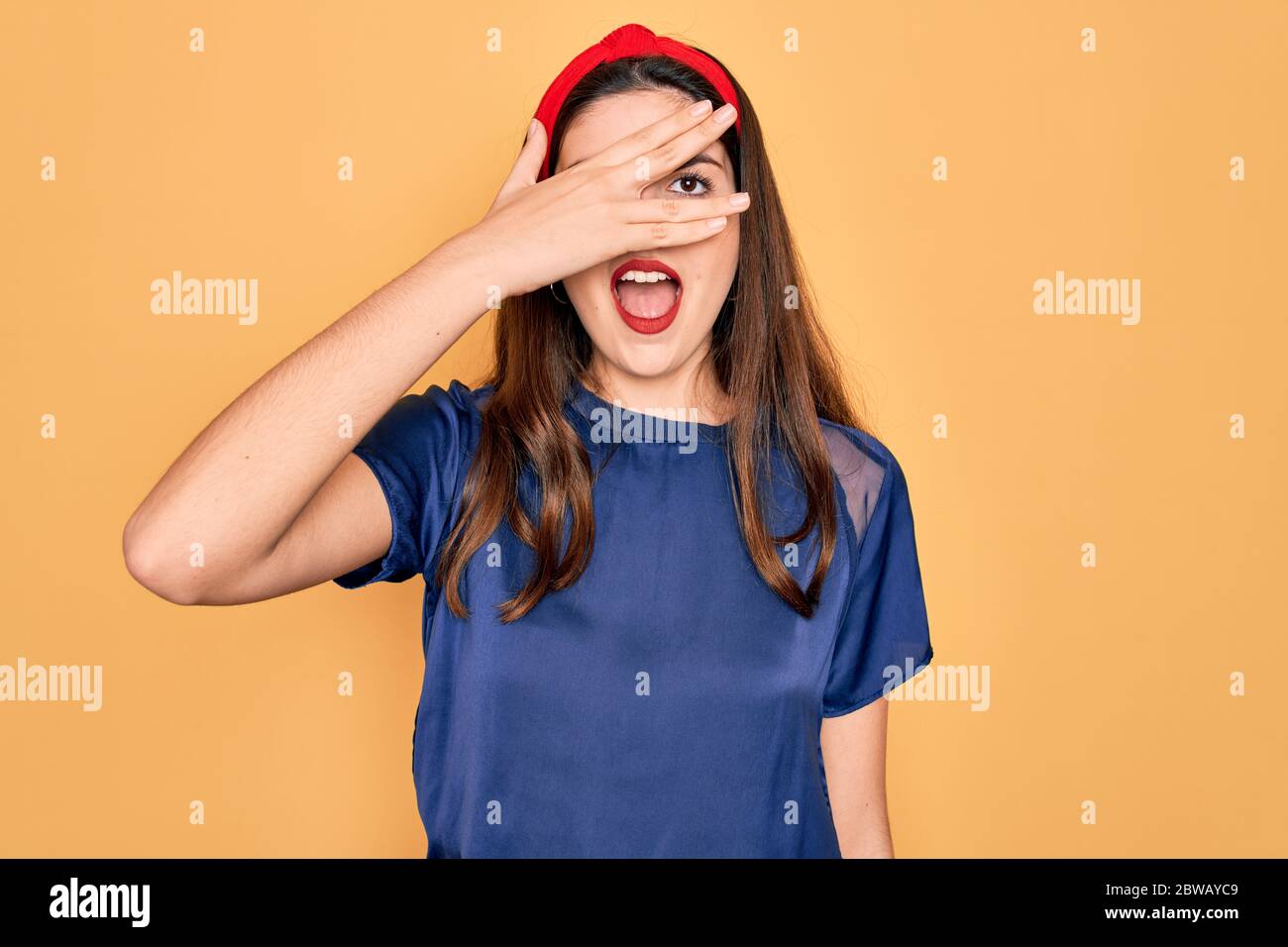 Young beautiful brunette woman wearing red lips over yellow background ...
