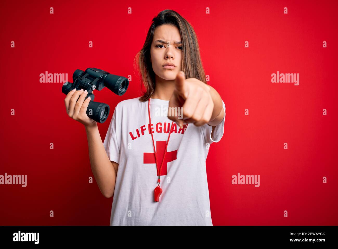 Young beautiful lifeguard girl wearing whistle using binoculars over ...