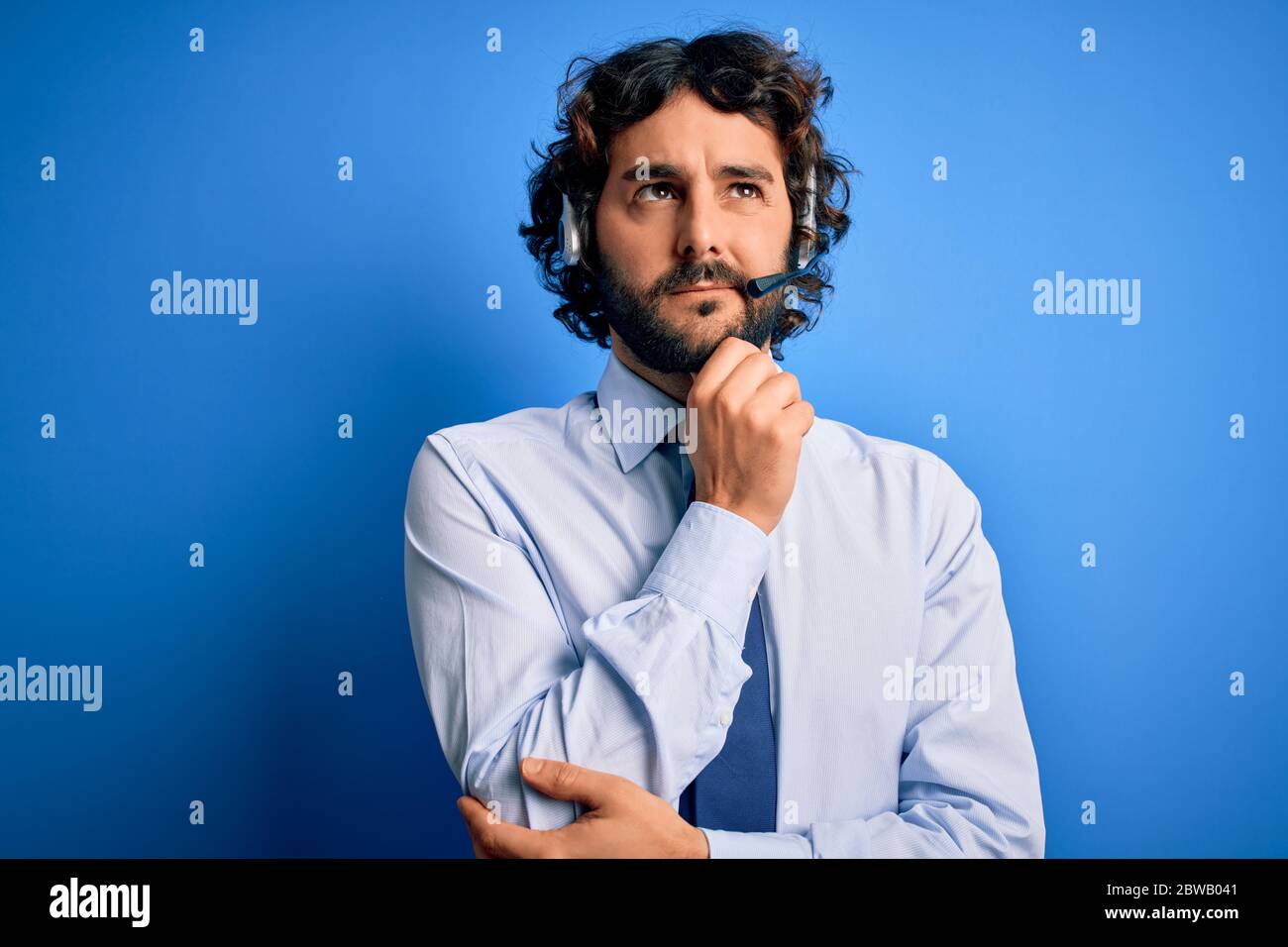 Young handsome call center agent man with beard working using headset ...