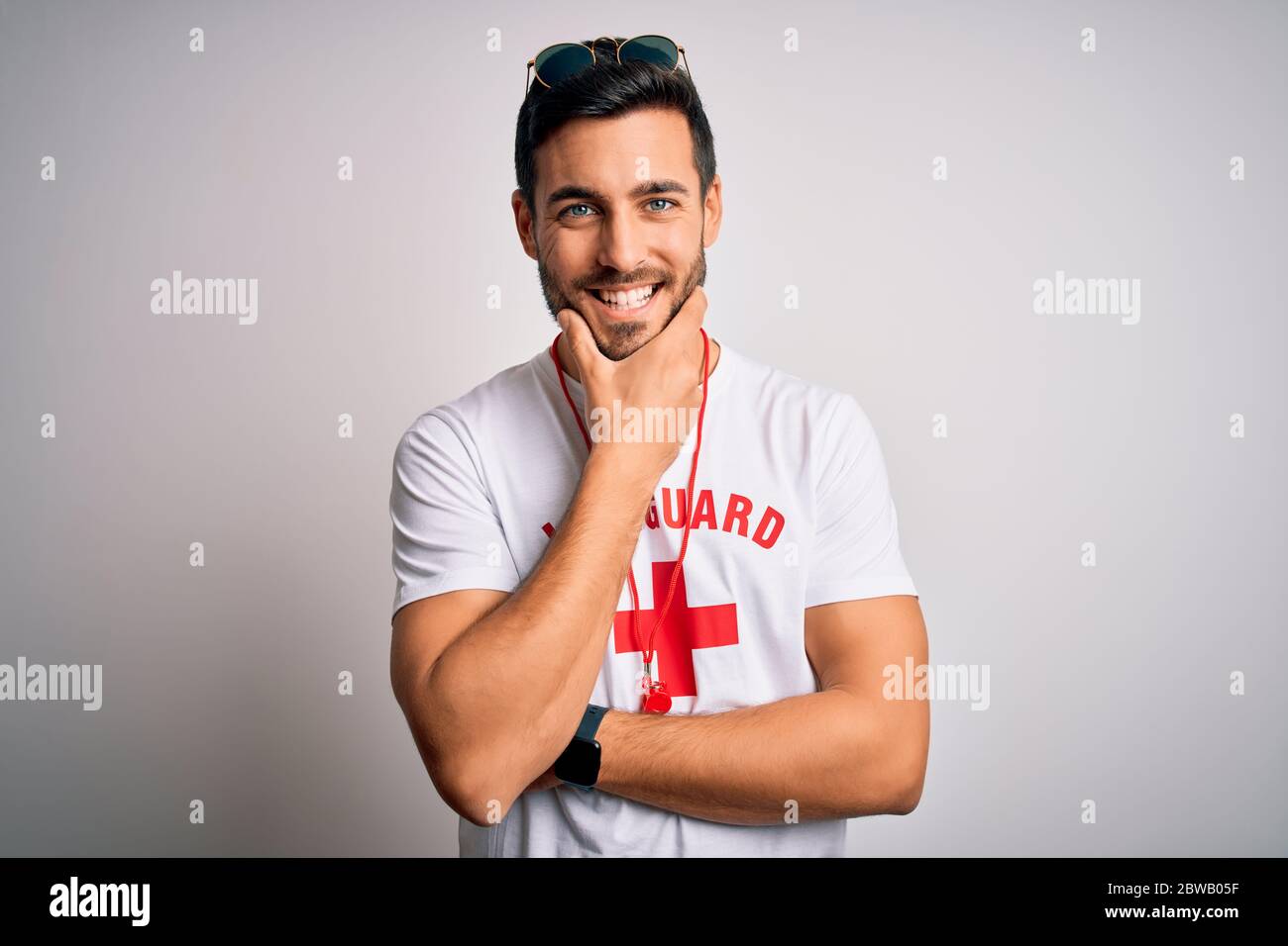 Young handsome lifeguard man with beard wearing t-shirt with red cross ...