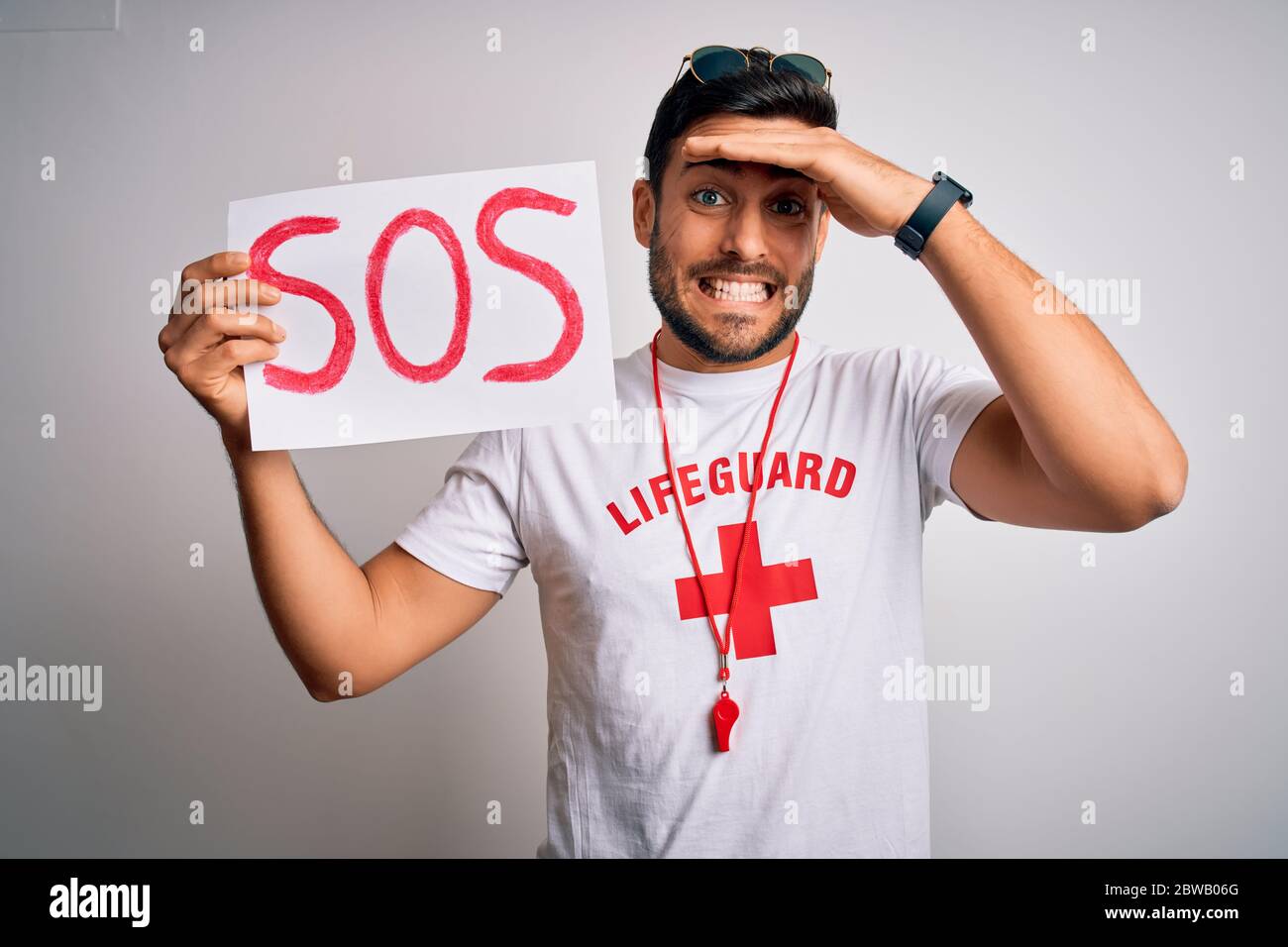 Young lifeguard man with beard wearing whistle holding paper with sos ...