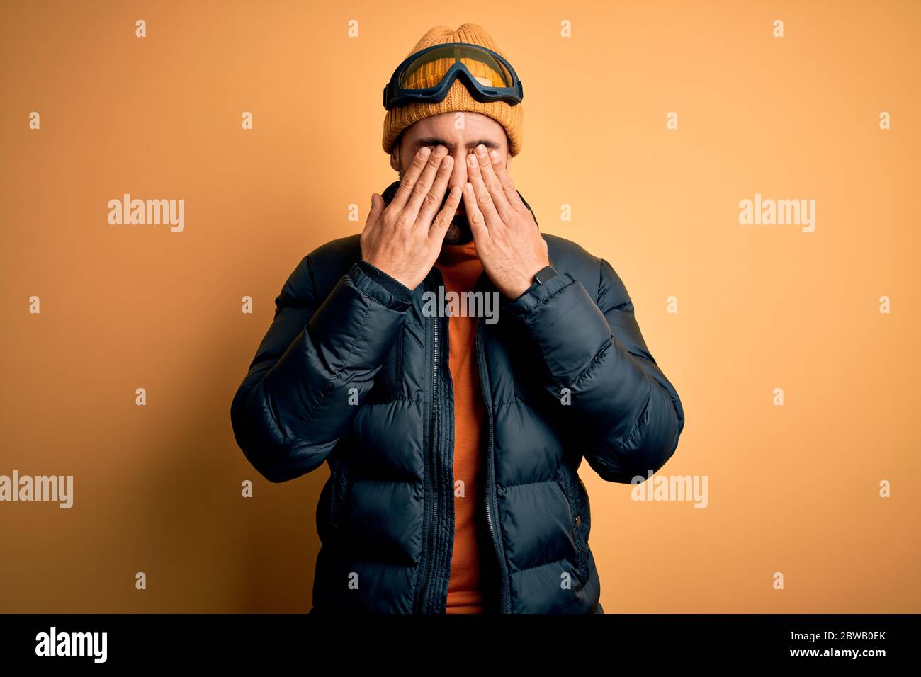 Young handsome skier man with beard wearing snow sportswear and ski ...