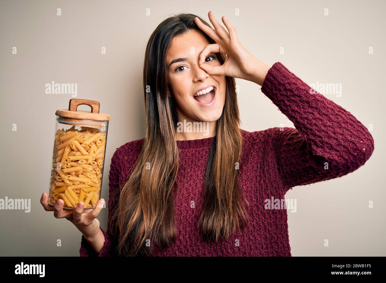 Young beautiful girl holding bottle of dry Italian pasta macaroni over ...