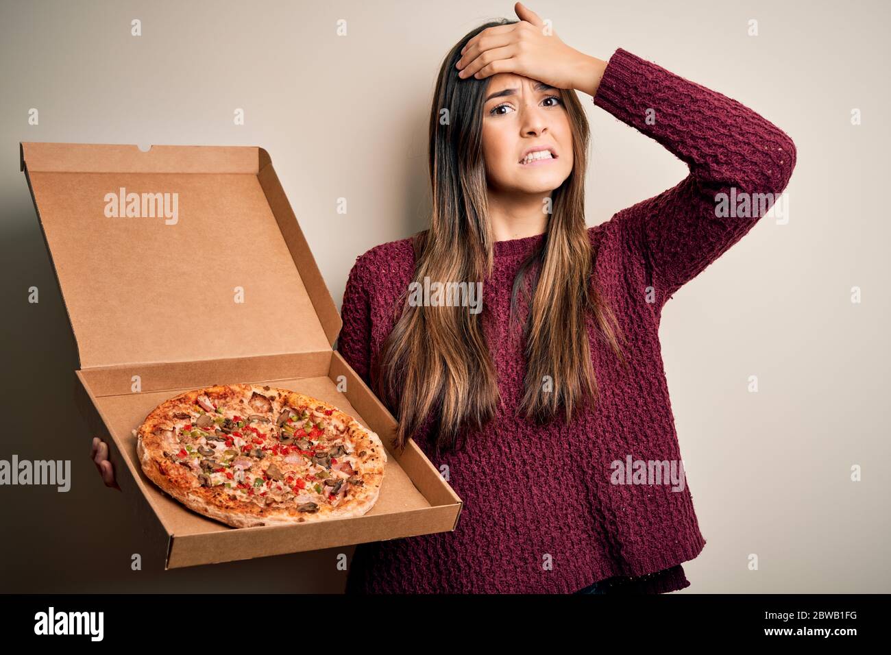 Young beautiful girl holding delivery box with Italian pizza standing ...