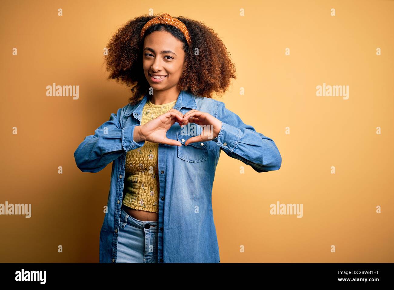 Beautiful african american with afro hair standing over yellow isolated ...
