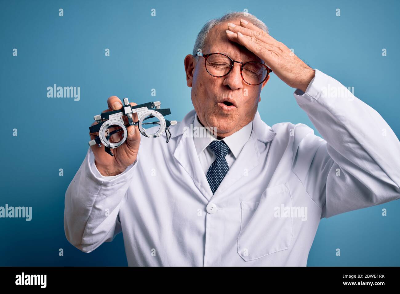 Senior grey haired optic doctor man holding optometrist eyeglasses over ...