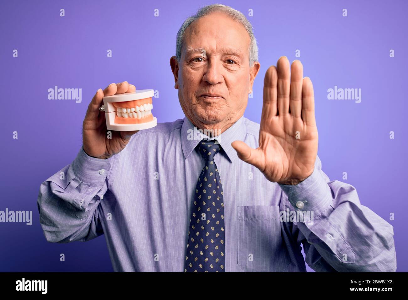 Grey haired senior man holding orthodontic prosthesis denture over ...