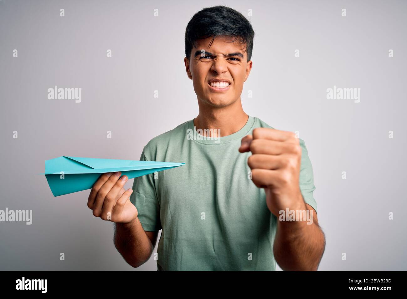 Young handsome man holding paper airplane over isolated white ...