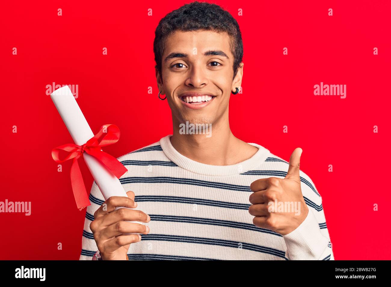 Young african amercian man holding graduate degree diploma smiling ...
