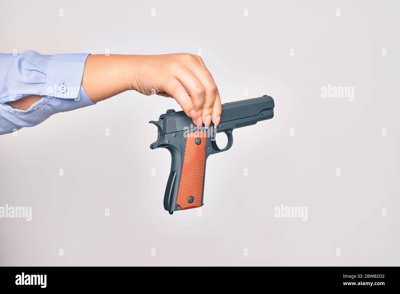Hand of caucasian young woman holding gun over isolated white ...