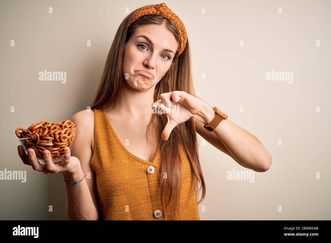 Young beautiful redhead woman holding bowl with german baked pretzels ...