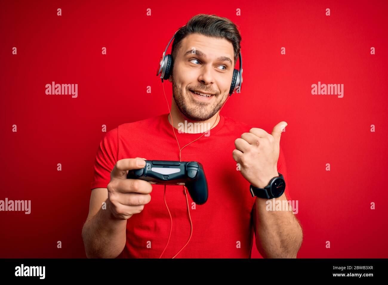 Young gamer man with blue eyes playing video games using gamepad ...