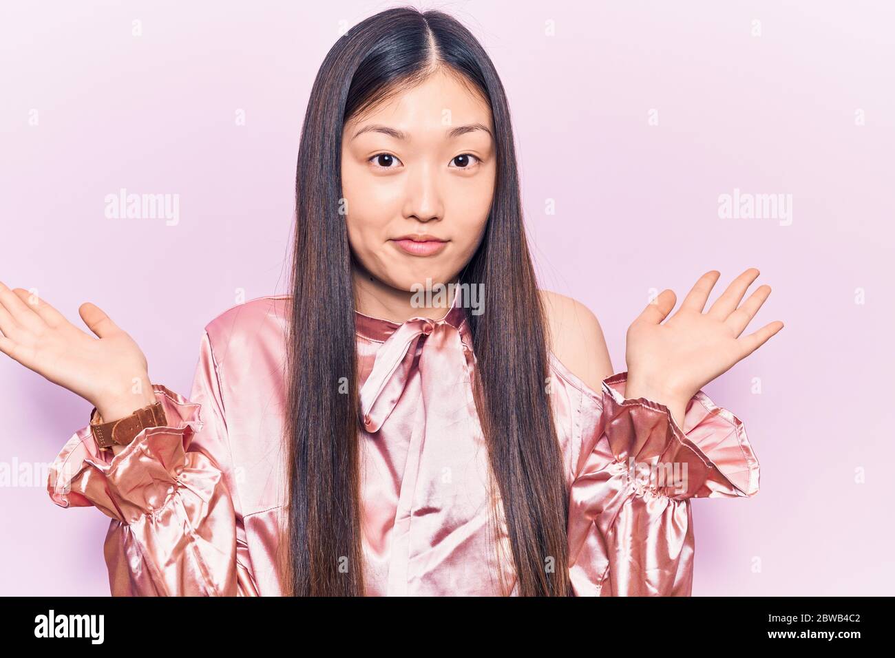 Young beautiful chinese woman wearing casual shirt clueless and ...