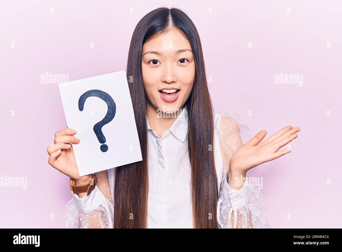 Young beautiful chinese woman holding question mark celebrating ...