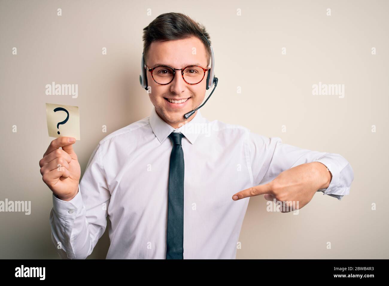 Young call center operator man wearing headset holding paper note with ...