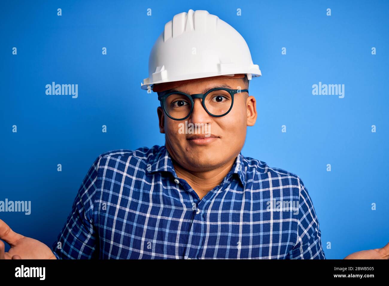 Young handsome engineer latin man wearing safety helmet over isolated ...