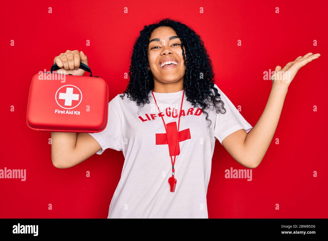Young african american curly lifeguard woman wearing whistle holding ...