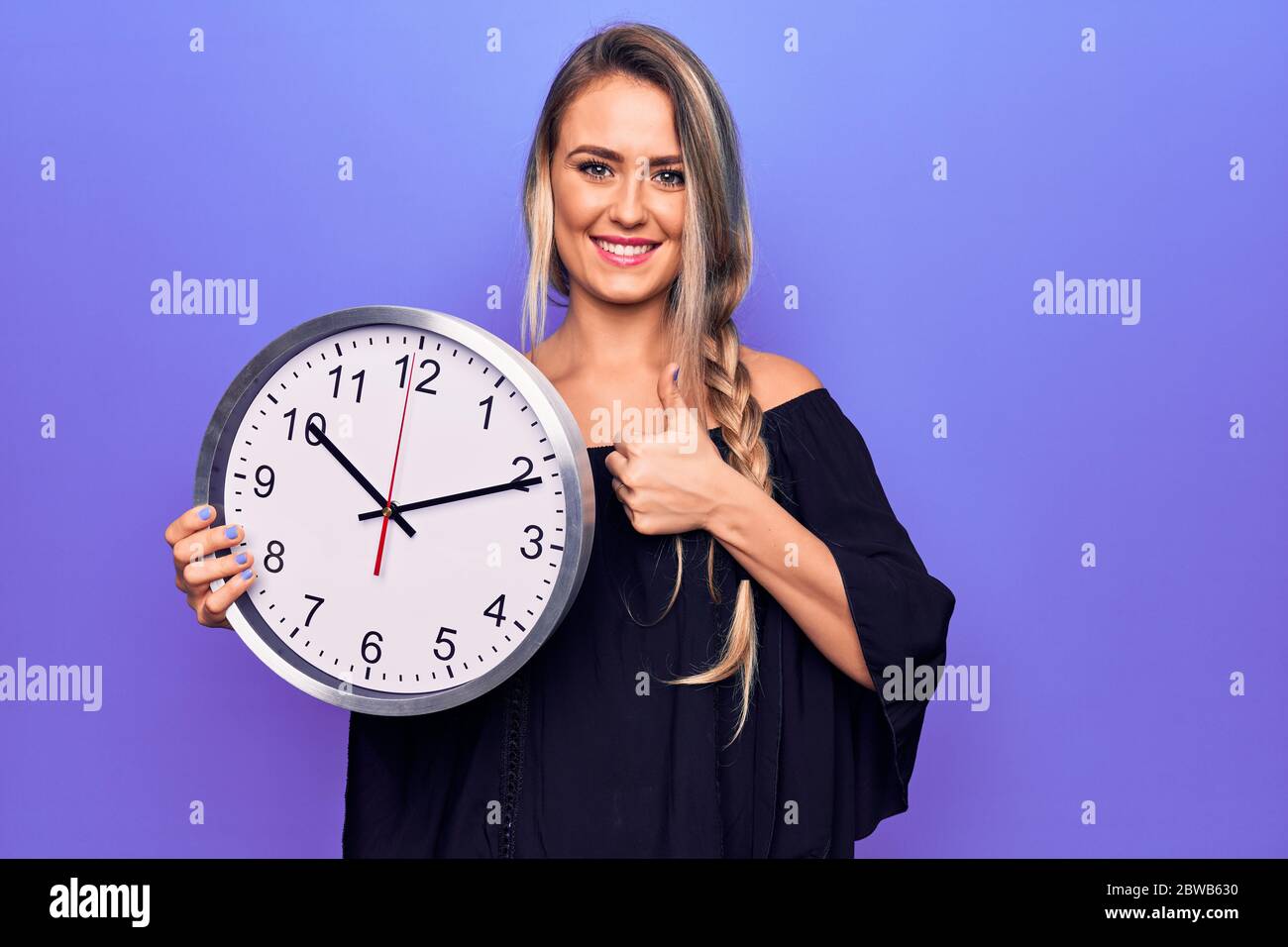 Young beautiful blonde woman doing countdown using big clock over ...