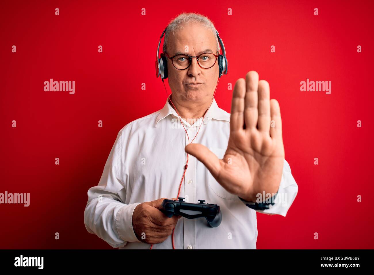 Middle age handsome hoary gamer man playing video game using joystick ...