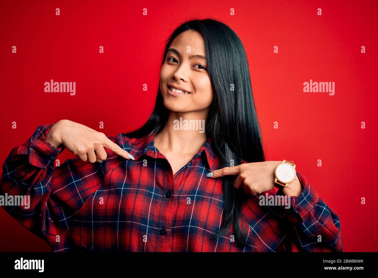 Young beautiful chinese woman wearing casual shirt over isolated red background looking ...