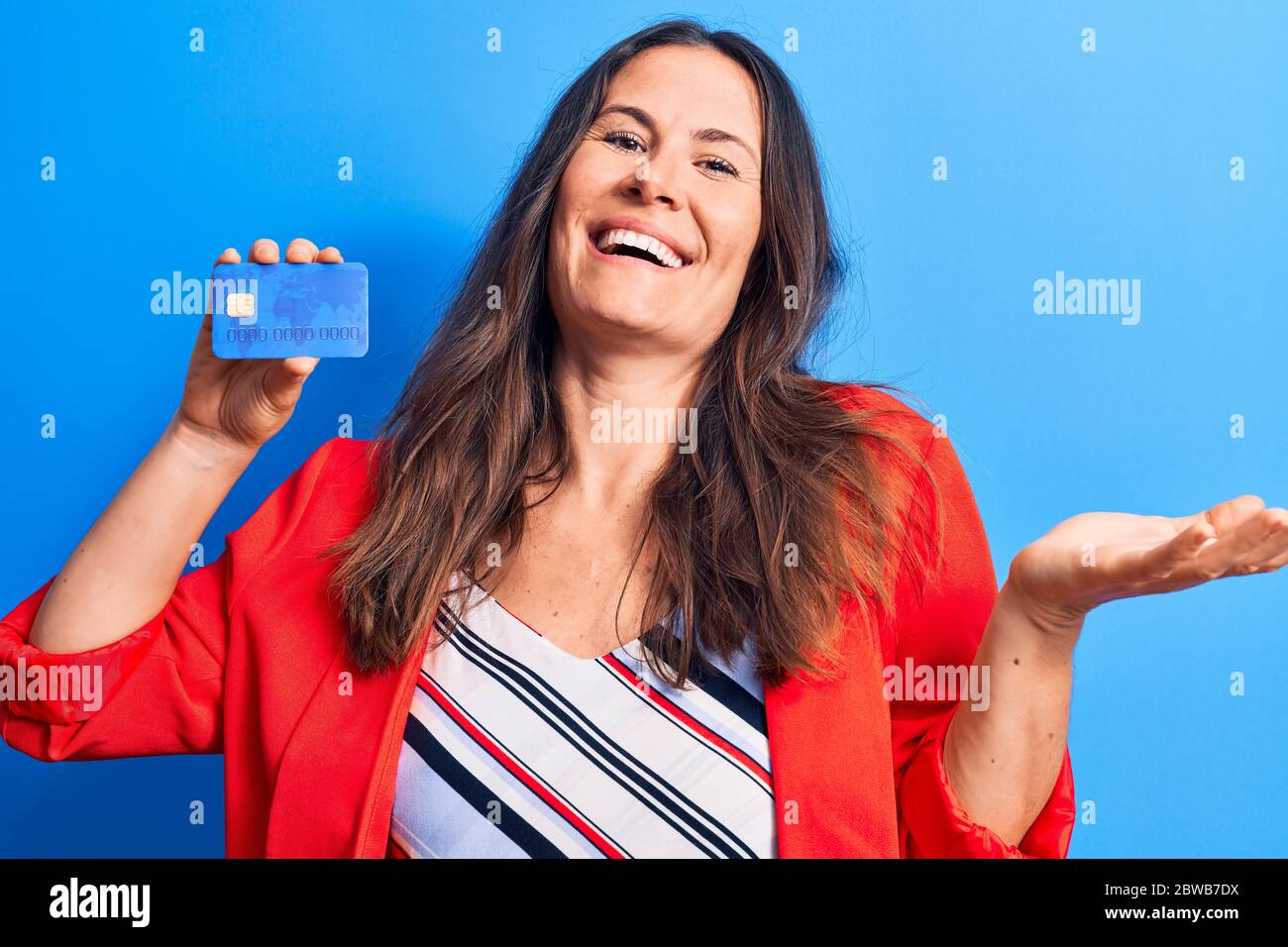 Young beautiful brunette businesswoman holding credit card over ...